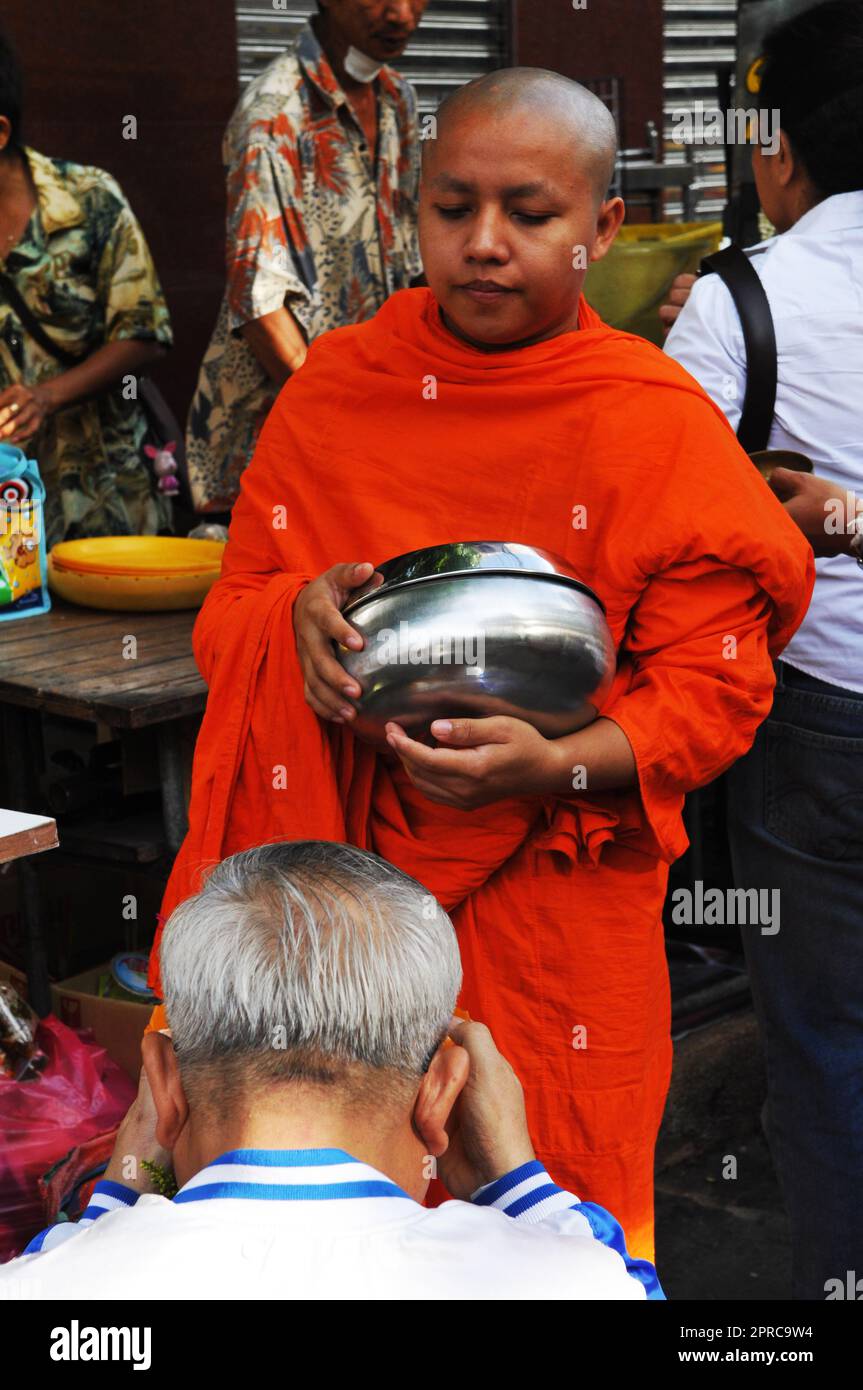 A Thai Buddhist monk blessing locals and receiving alms as part of a ...