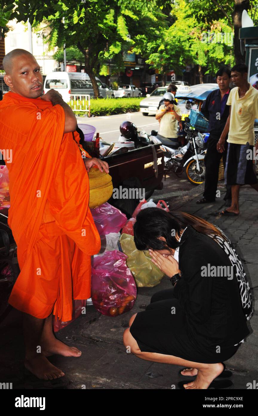 A Thai Buddhist monk blessing locals and receiving alms as part of a ...
