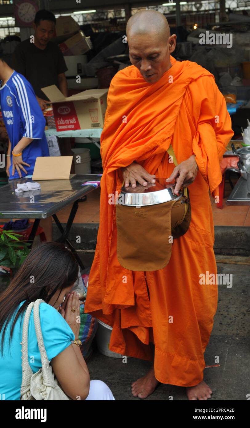 A Thai Buddhist monk blessing locals and receiving alms as part of a ...