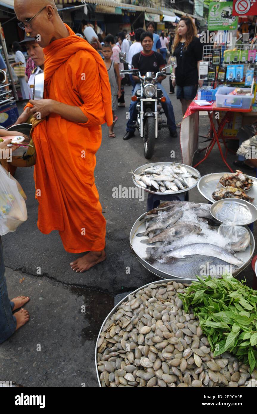 A Thai Buddhist monk blessing locals and receiving alms as part of a ...