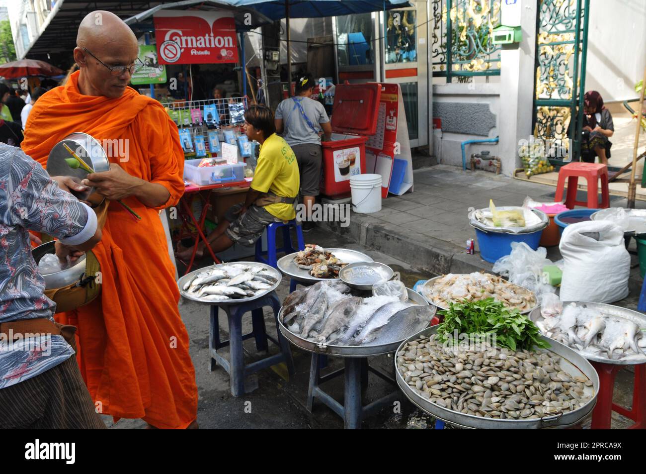 A Thai Buddhist monk blessing locals and receiving alms as part of a ...