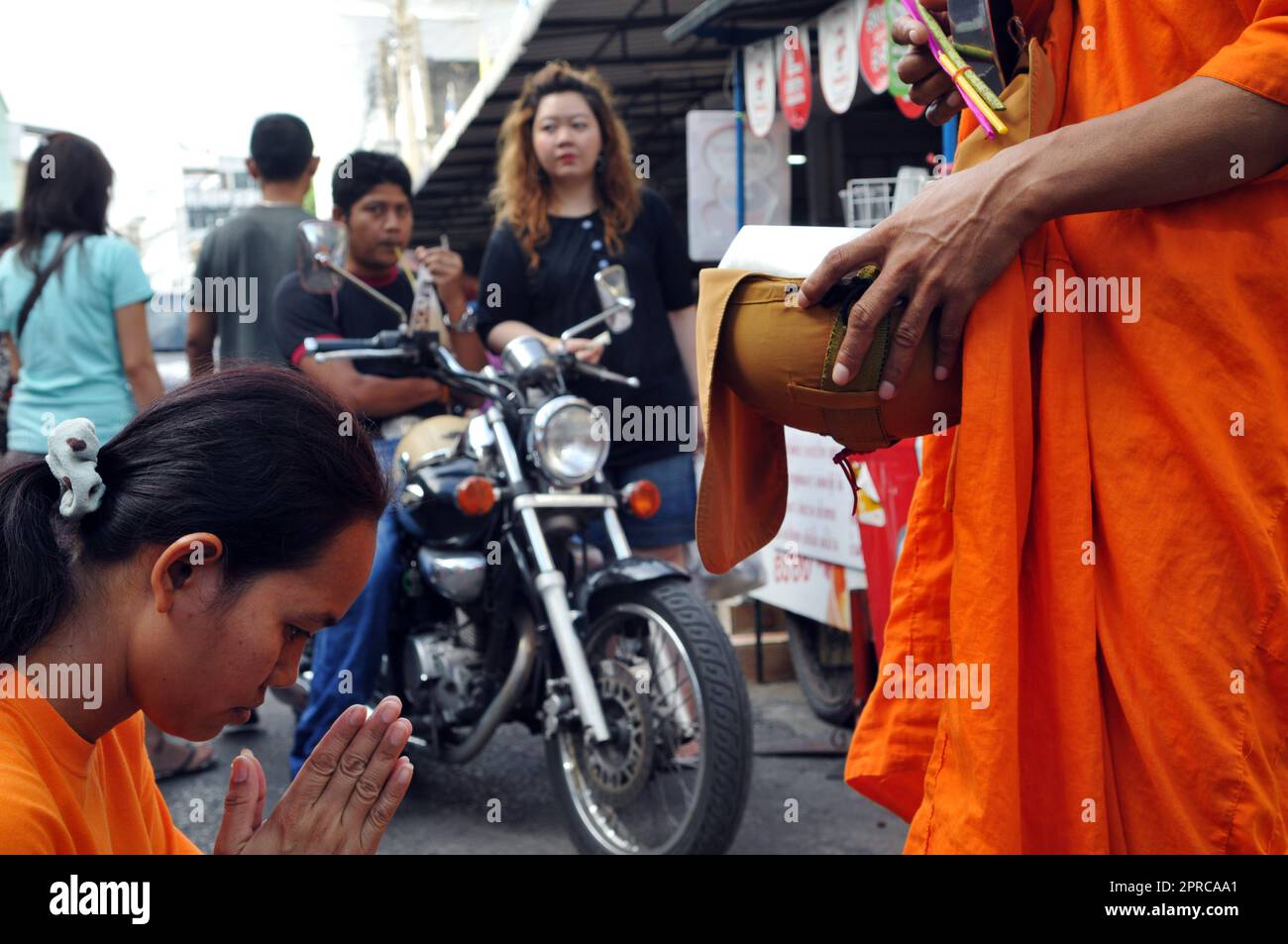 A Thai Buddhist monk blessing locals and receiving alms as part of a ...