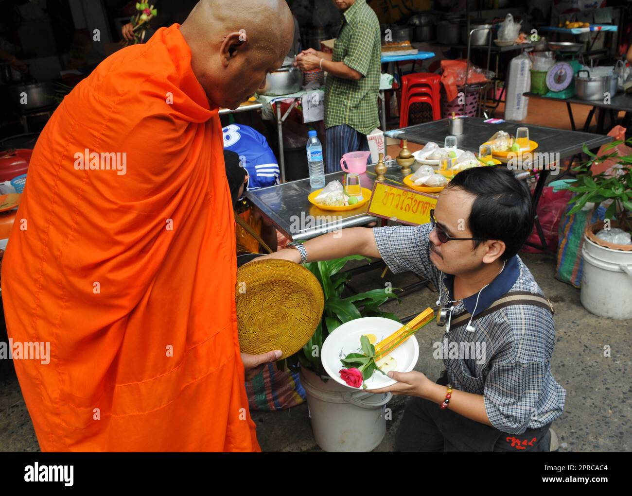 A Thai Buddhist monk blessing locals and receiving alms as part of a ...