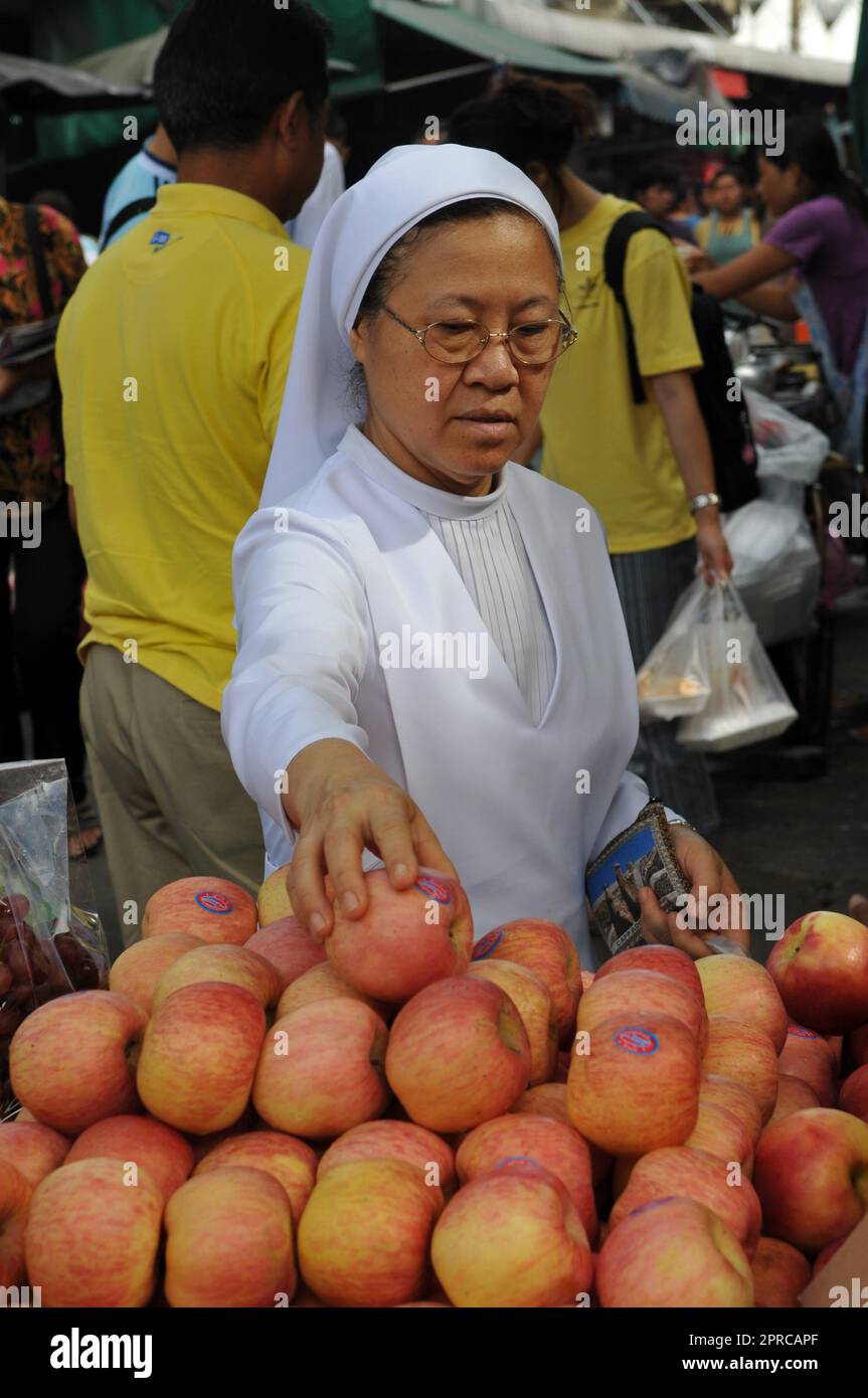 A Catholic nun buying apples at the Soi Prachum market by Silom Road in ...