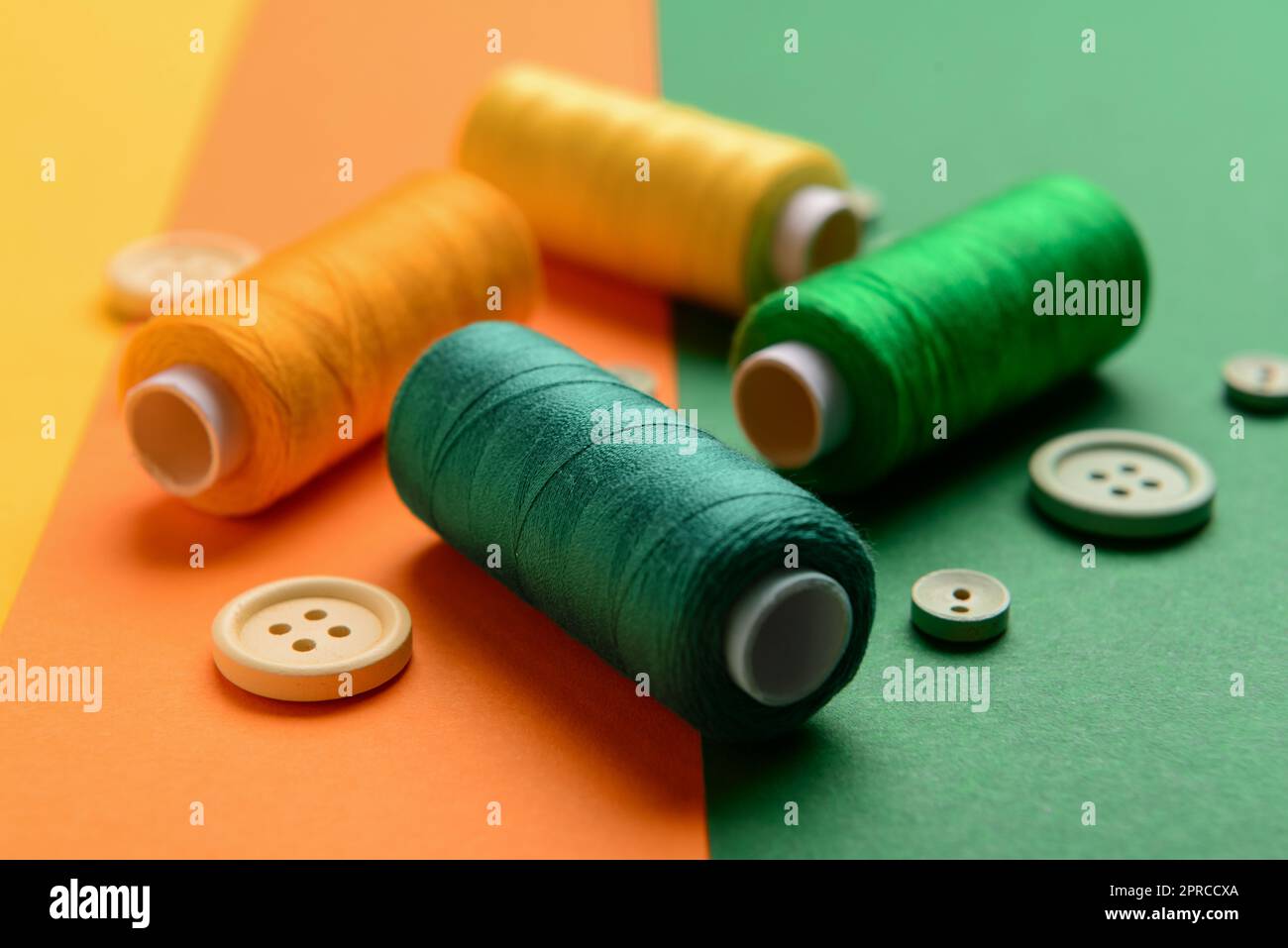 Set of thread spools and buttons on color background Stock Photo - Alamy