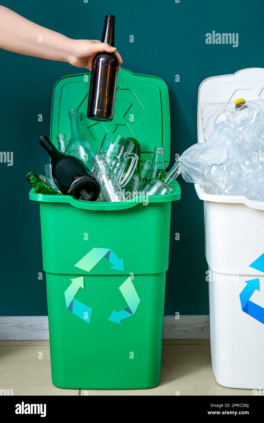 Woman throwing garbage into trash bin near green wall. Recycling ...