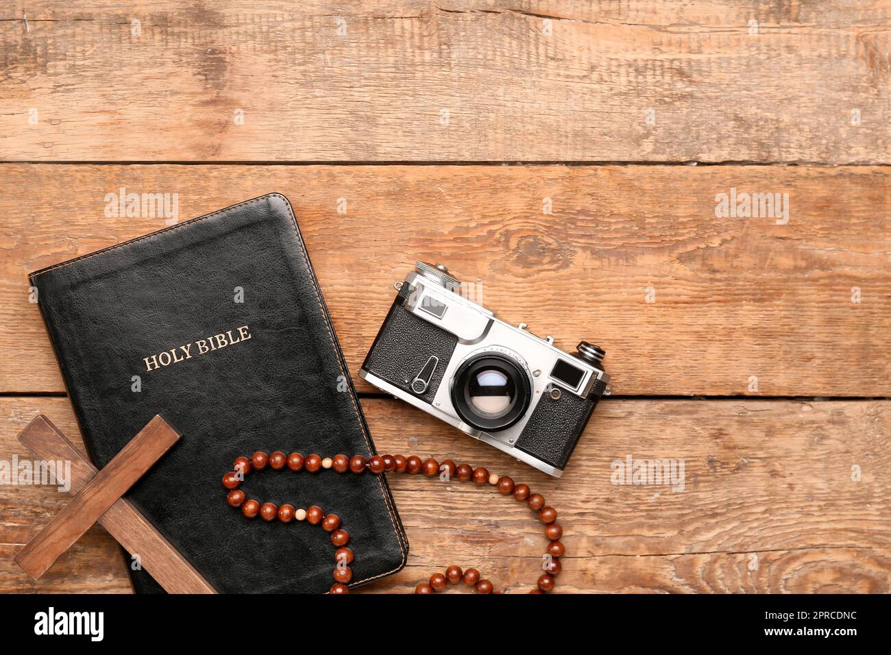 Holy Bible with photo camera, prayer beads and cross on wooden ...