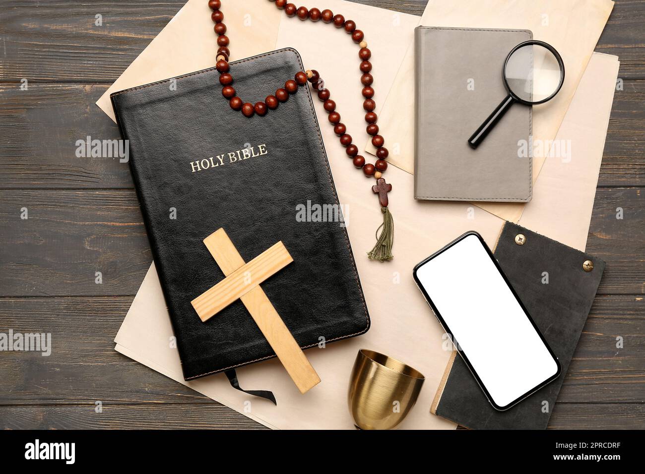 Holy Bible with prayer beads, cross, mobile phone, notebooks and paper ...