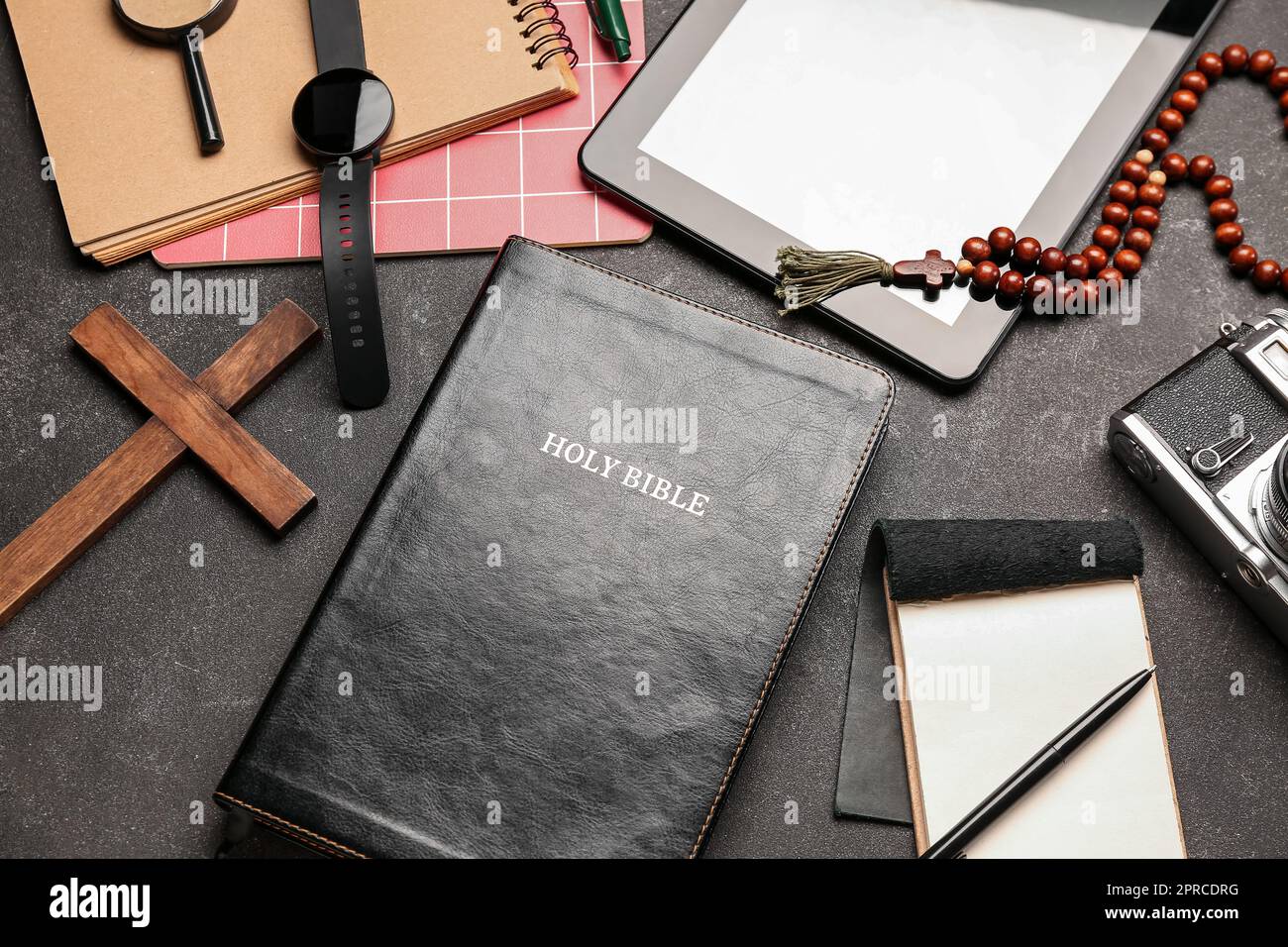 Holy Bible with prayer beads, tablet computer, smartwatch, notebooks ...