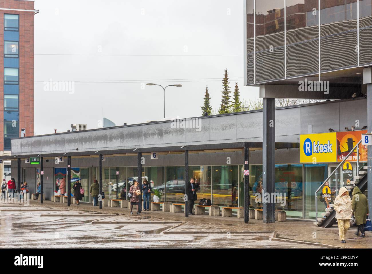 Passengers waiting for thw buses at bus station in a drizzle in Tartu ...