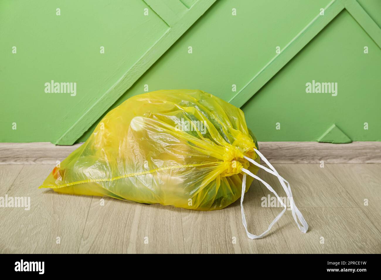 Full garbage bag near green wall Stock Photo - Alamy