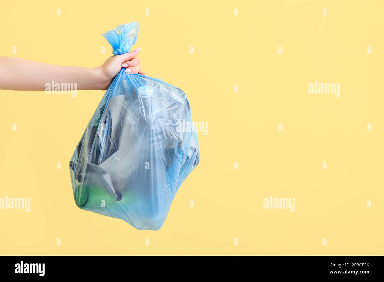 Female hand holding full garbage bag on yellow background Stock Photo ...