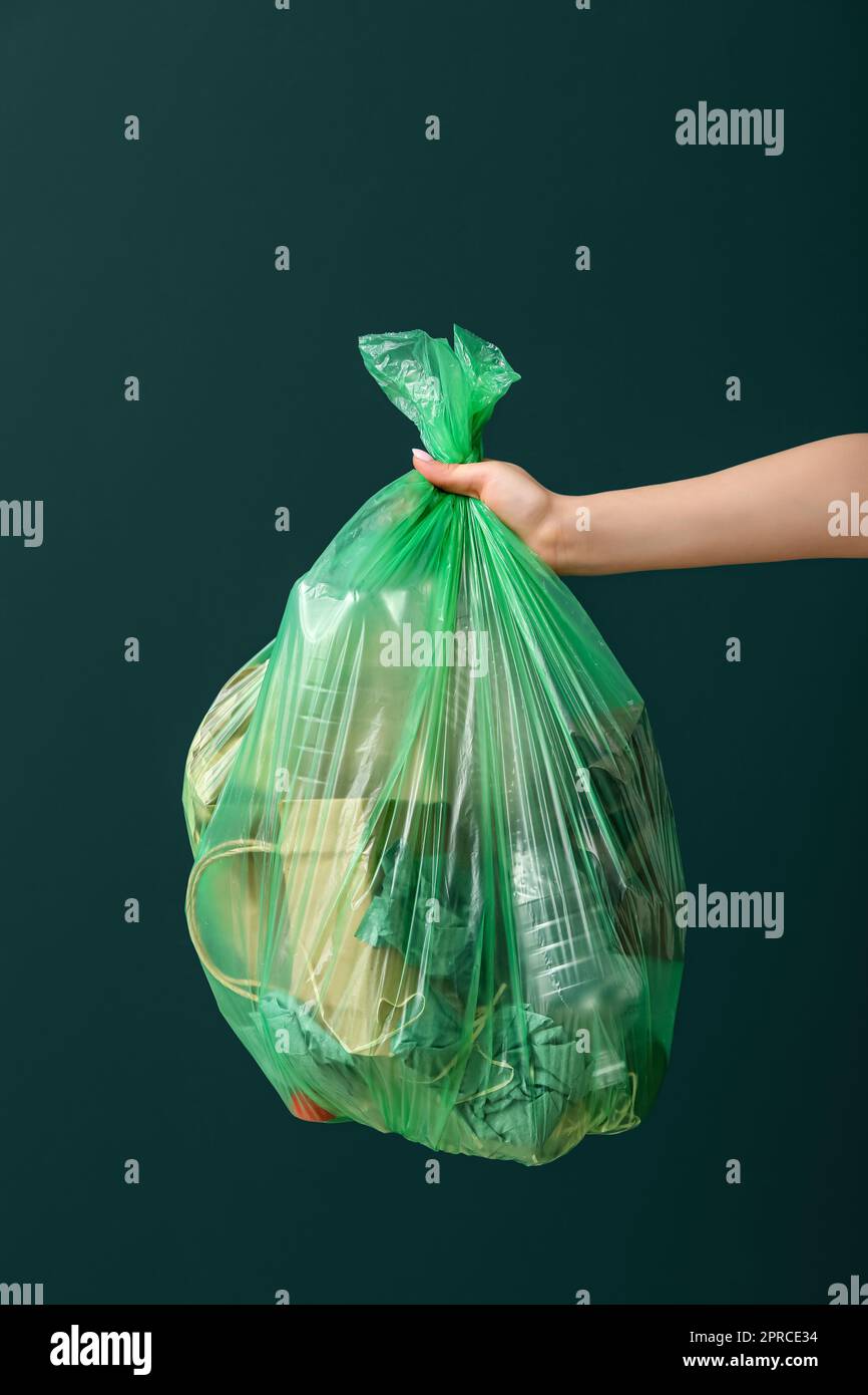 Female hand holding full garbage bag on green background Stock Photo ...