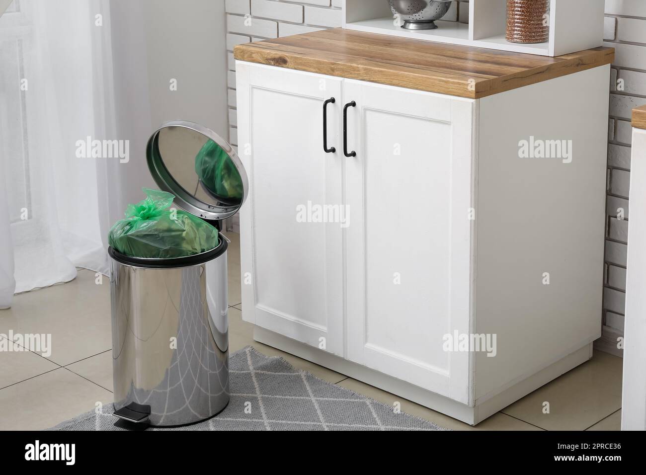 Full trash bin in interior of modern kitchen Stock Photo - Alamy