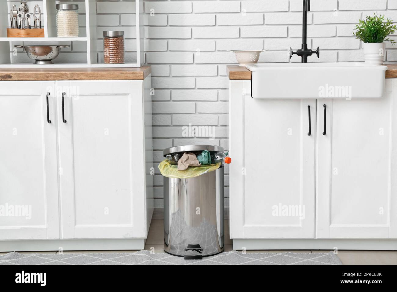 Full trash bin in interior of modern kitchen Stock Photo - Alamy