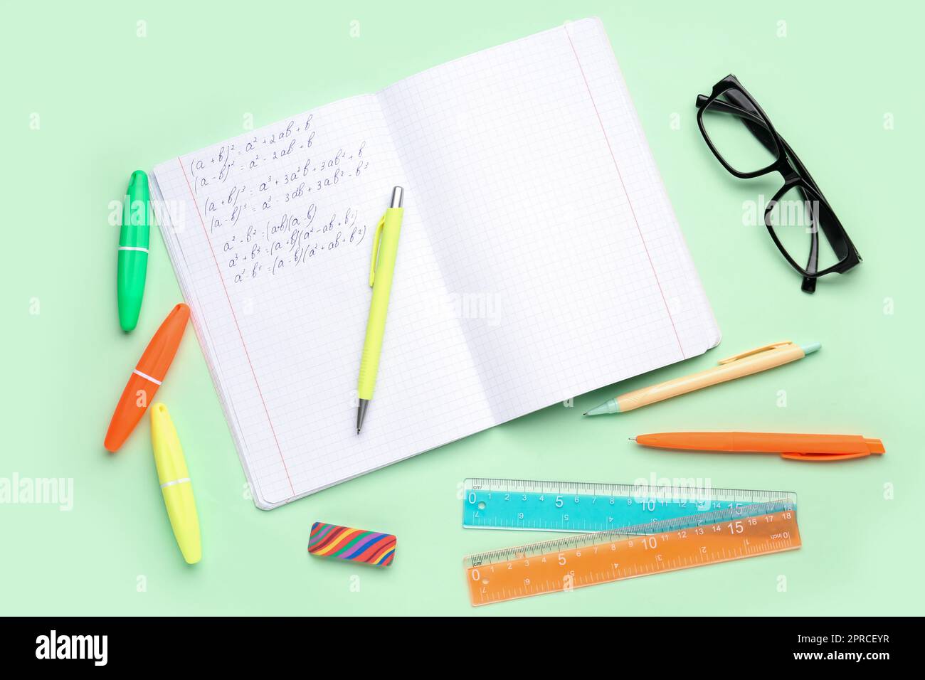 Copybook with maths formulas, glasses and stationery on green ...