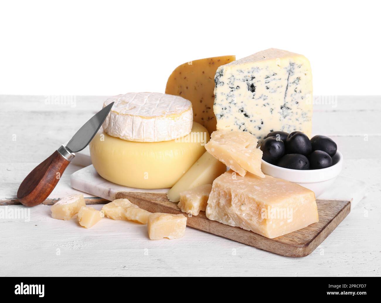 Board with different types of tasty cheese on table against white ...