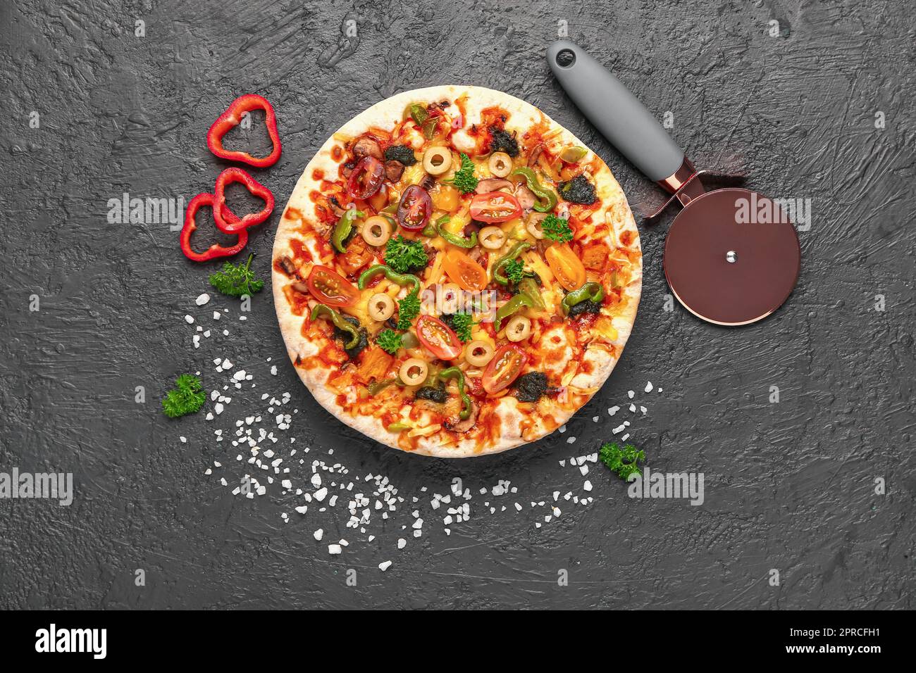 Vegetable pizza with cutter on dark background Stock Photo - Alamy