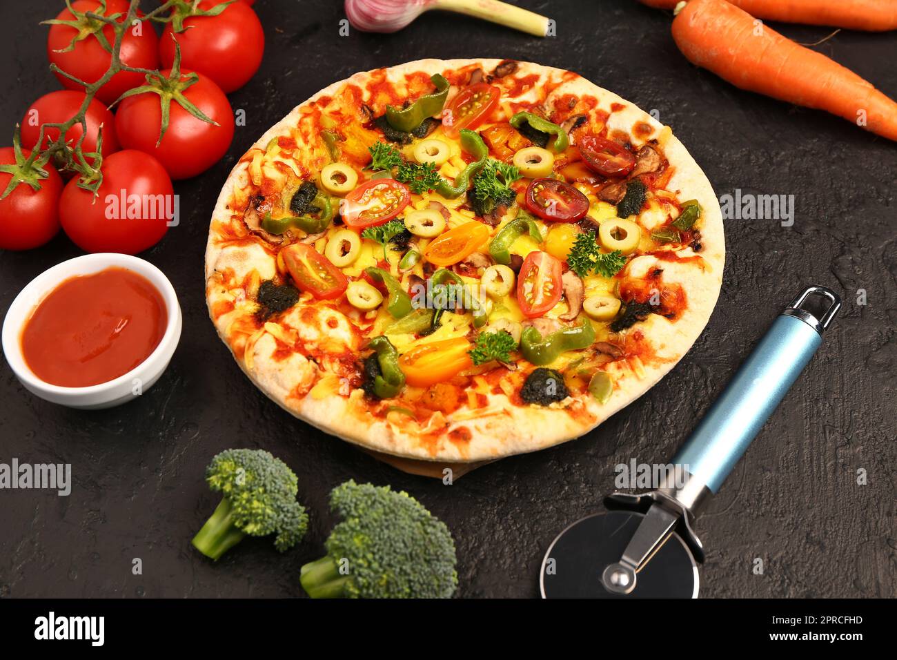 Vegetable pizza with ingredients and cutter on dark background Stock ...