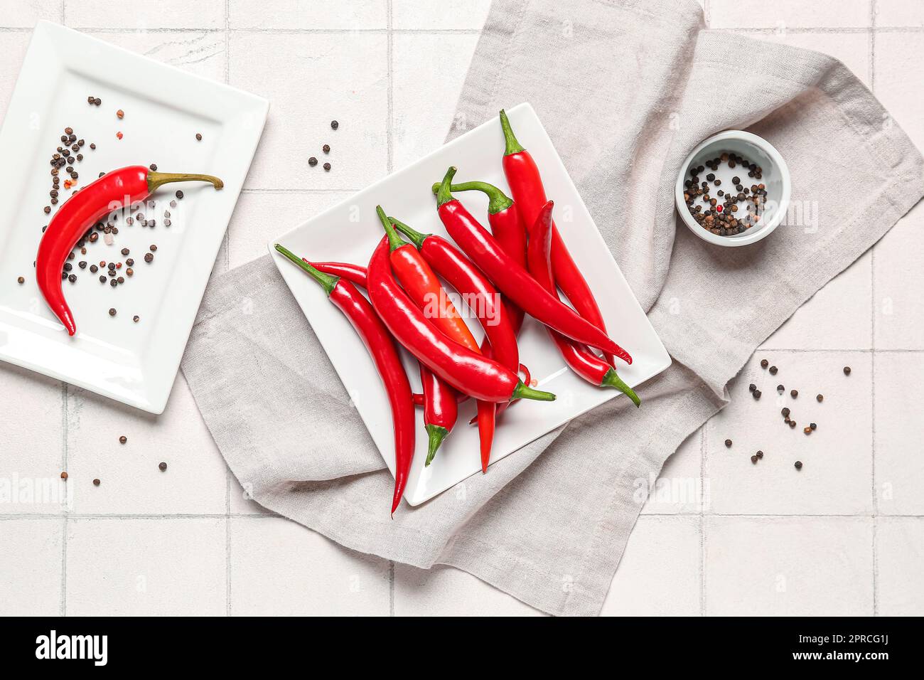 Plates with fresh chili peppers on light tile background Stock Photo ...