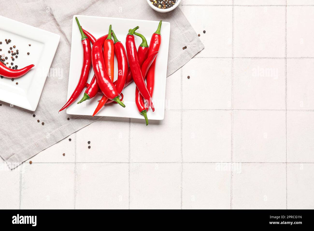 Plates with fresh chili peppers on light tile background Stock Photo ...