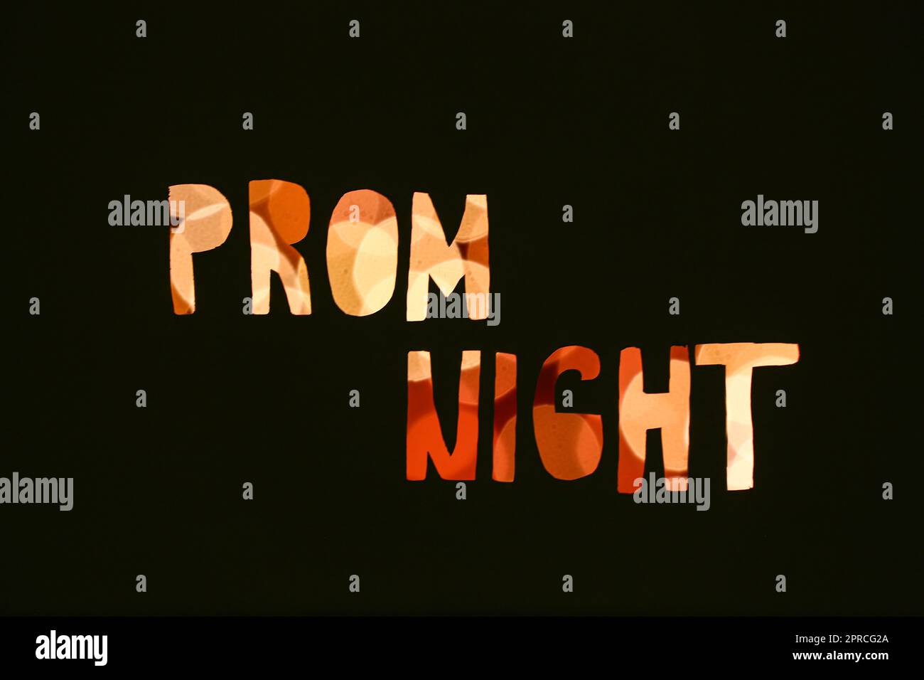 Blurred lights visible through cut black paper with text PROM NIGHT ...