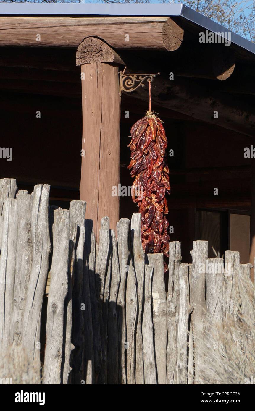 A red chili ristra, a string of chili peppers, hangs from the eave of a ...