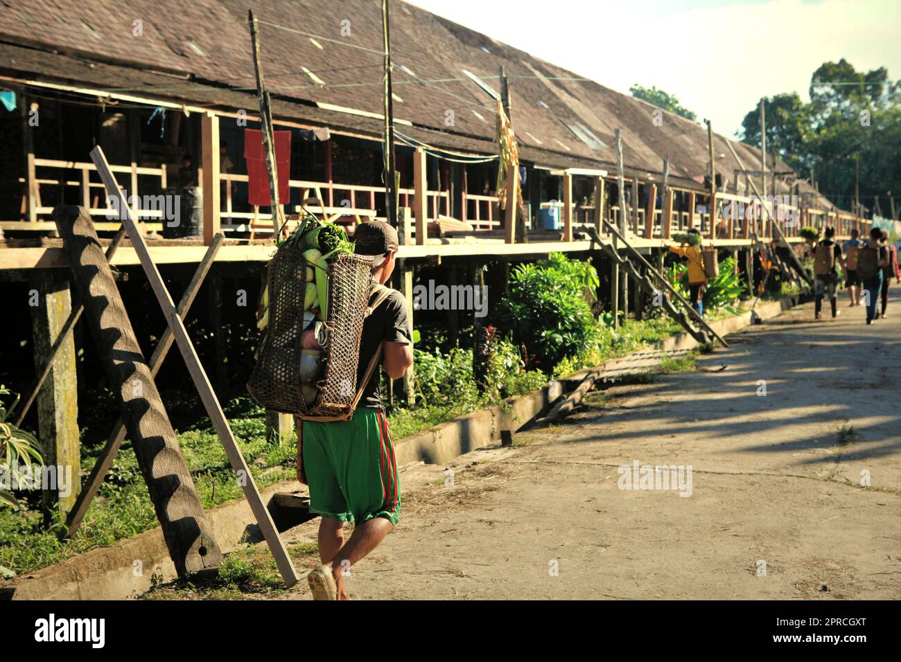 A man carries load in his rattan bag as he is going for a group ...