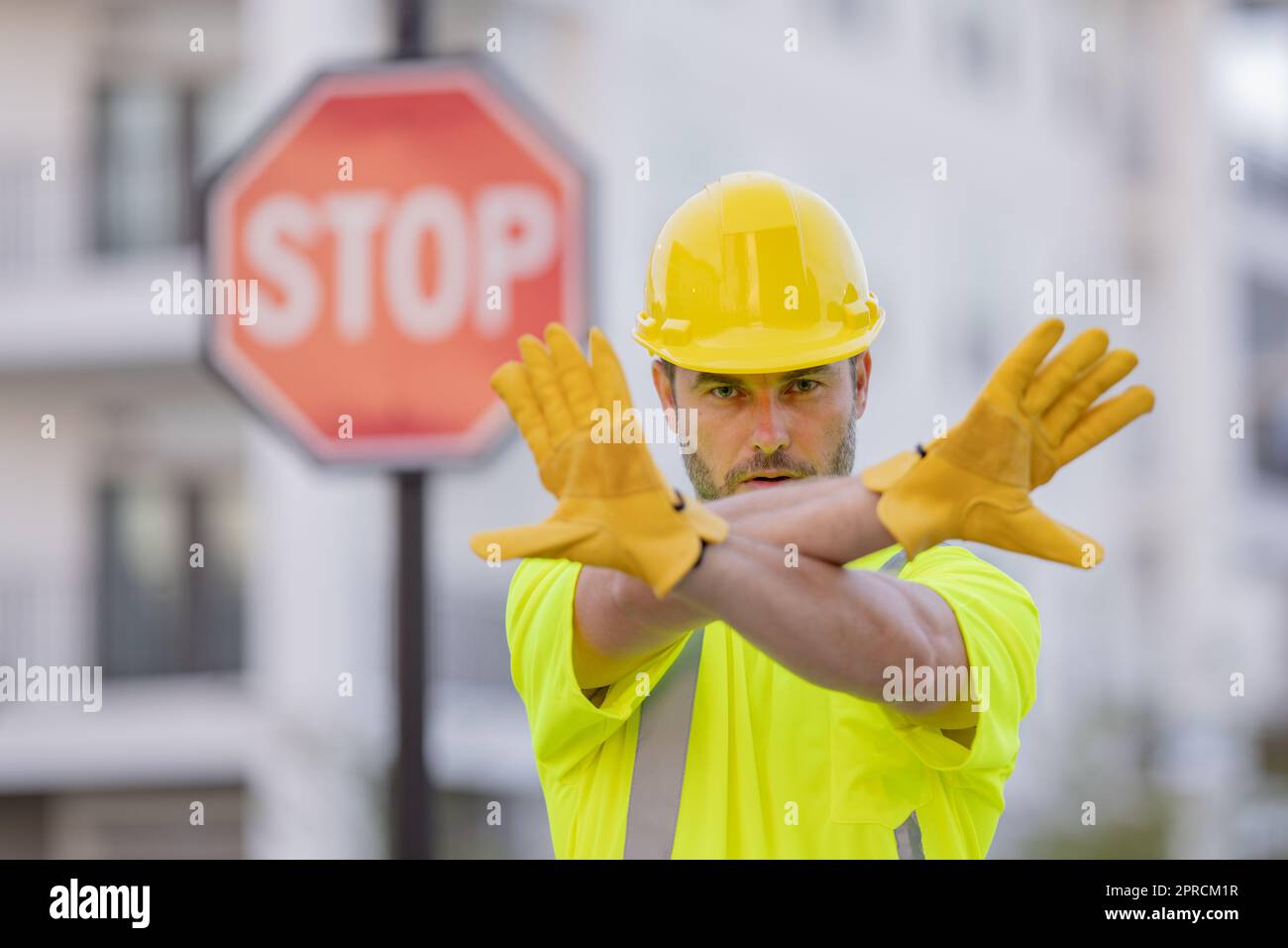 Worker builder with stop road sign. Man in hardhat helmet doing stop ...