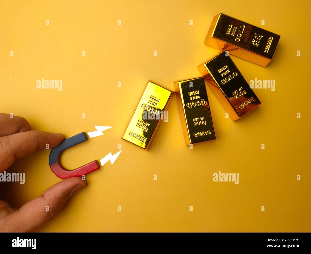 Hand holding magnet attract the gold bar on a yellow background Stock ...