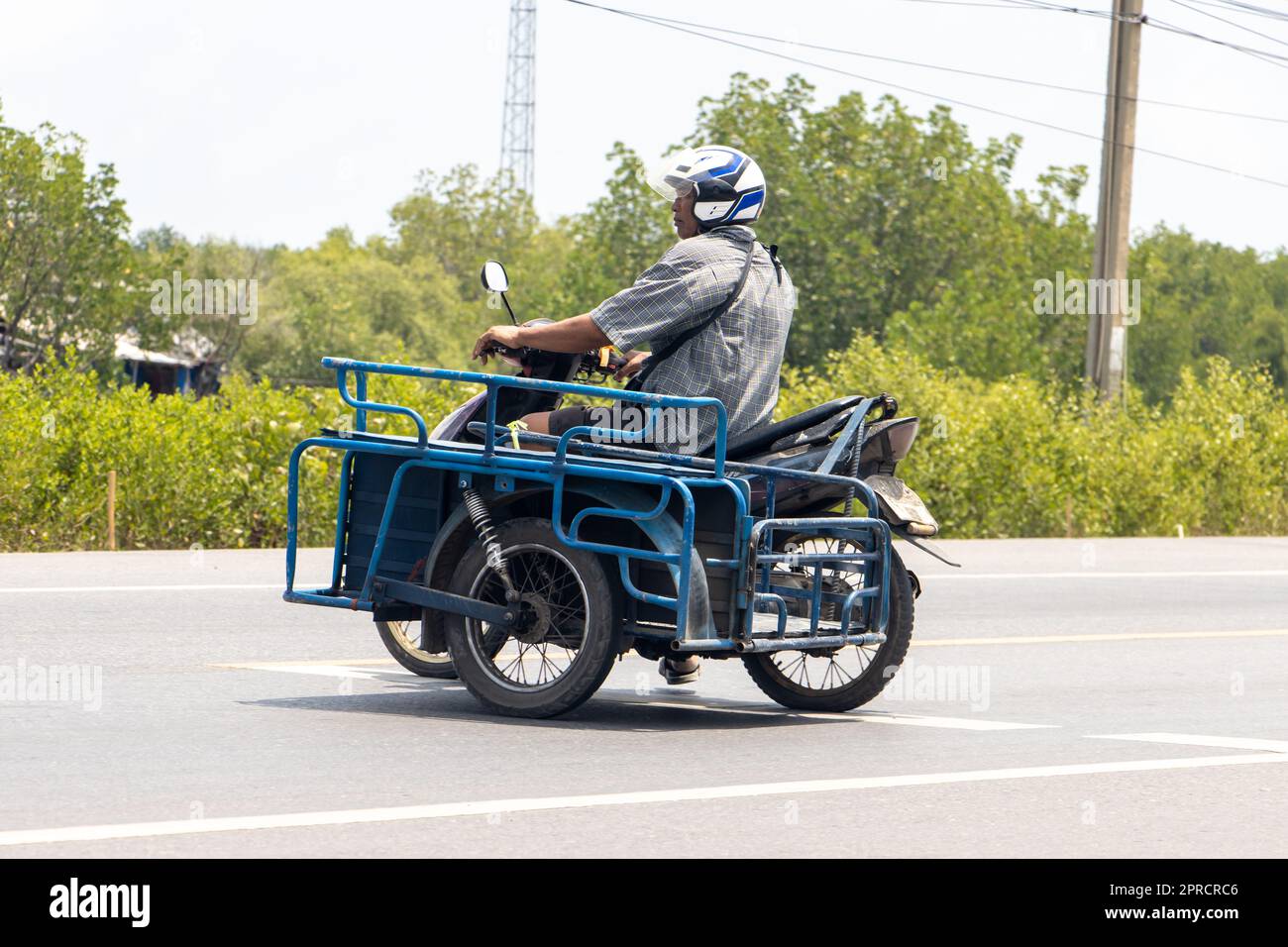 BANGKOK, THAILAND, MAR 24 2023, A motorcycle driver with a cart turns ...