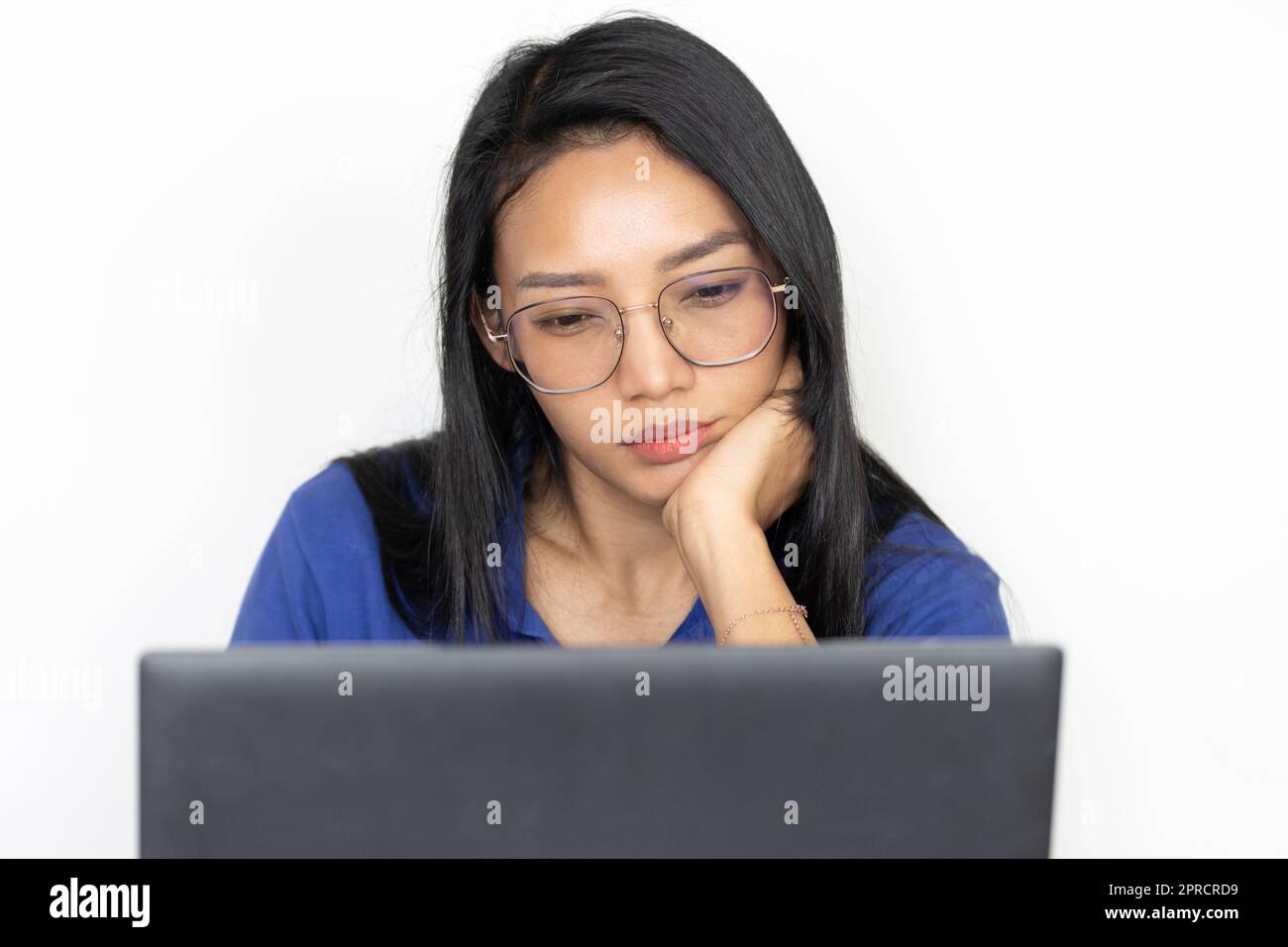 Thoughtful apathic woman working on laptop with head lean on hand Stock ...