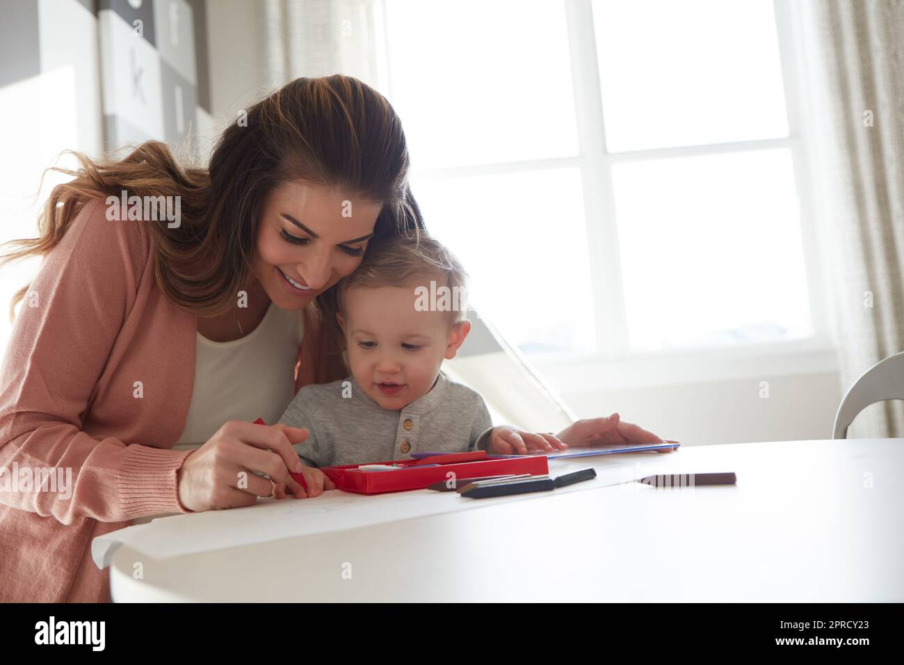 They learn through play. a woman and her young son using crayons to ...