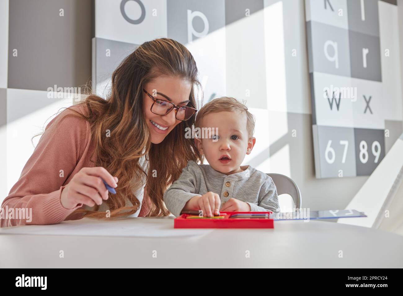 Learning begins at home. a woman and her young son using crayons to ...