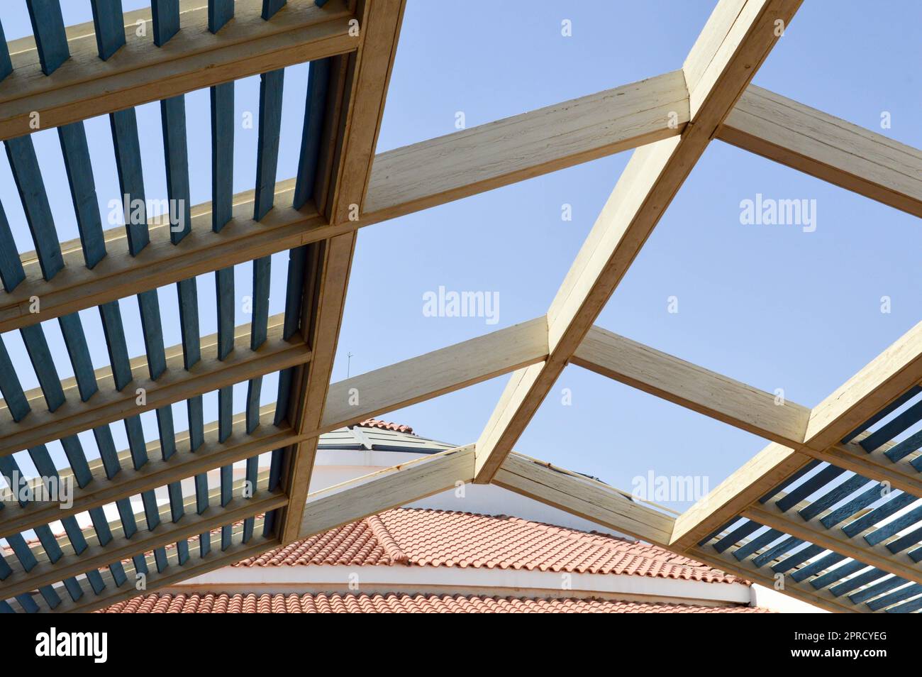 A wooden roof is modern from the sun with boards with beams and holes ...