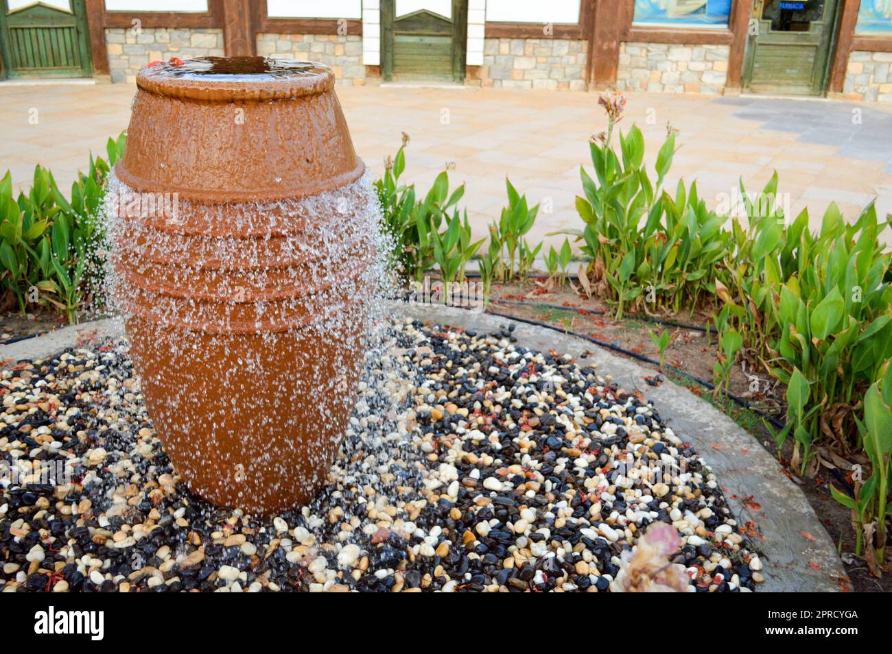 A beautiful little fountain in the form of a brown vase, a jug with ...