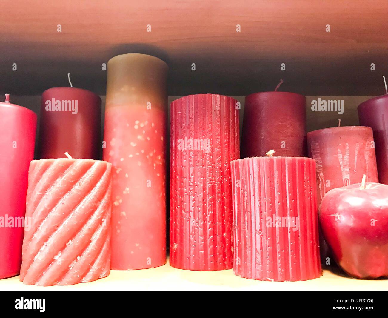 Texture of many festive different forms of red, burgundy wax candles ...