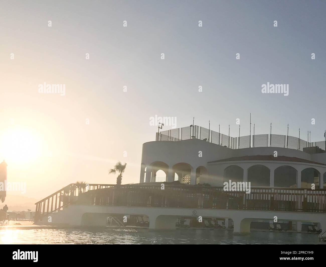 A large stone building near the water, a pool against the blue sky and ...
