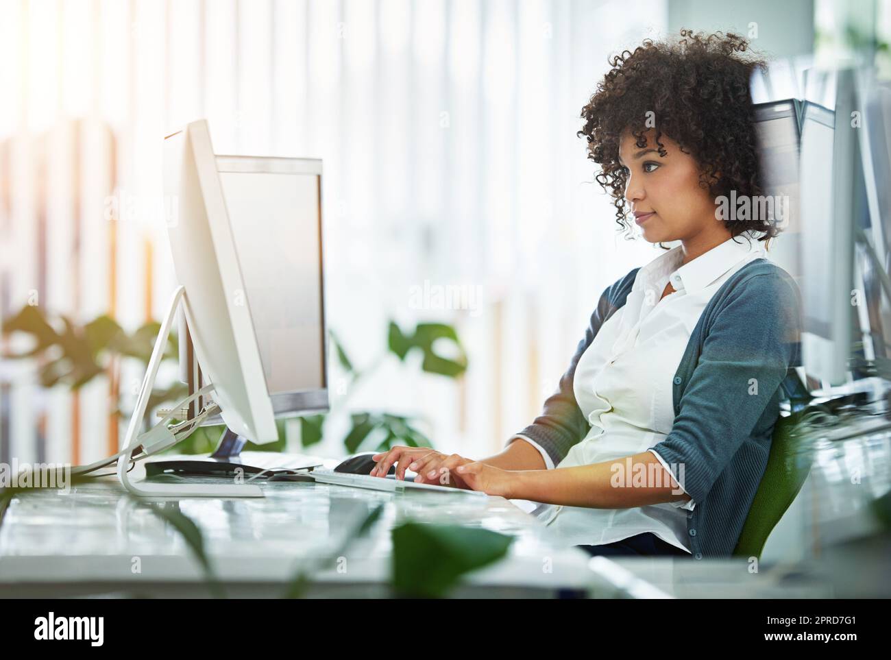 Young female designer working at her computer by a desk in a modern ...