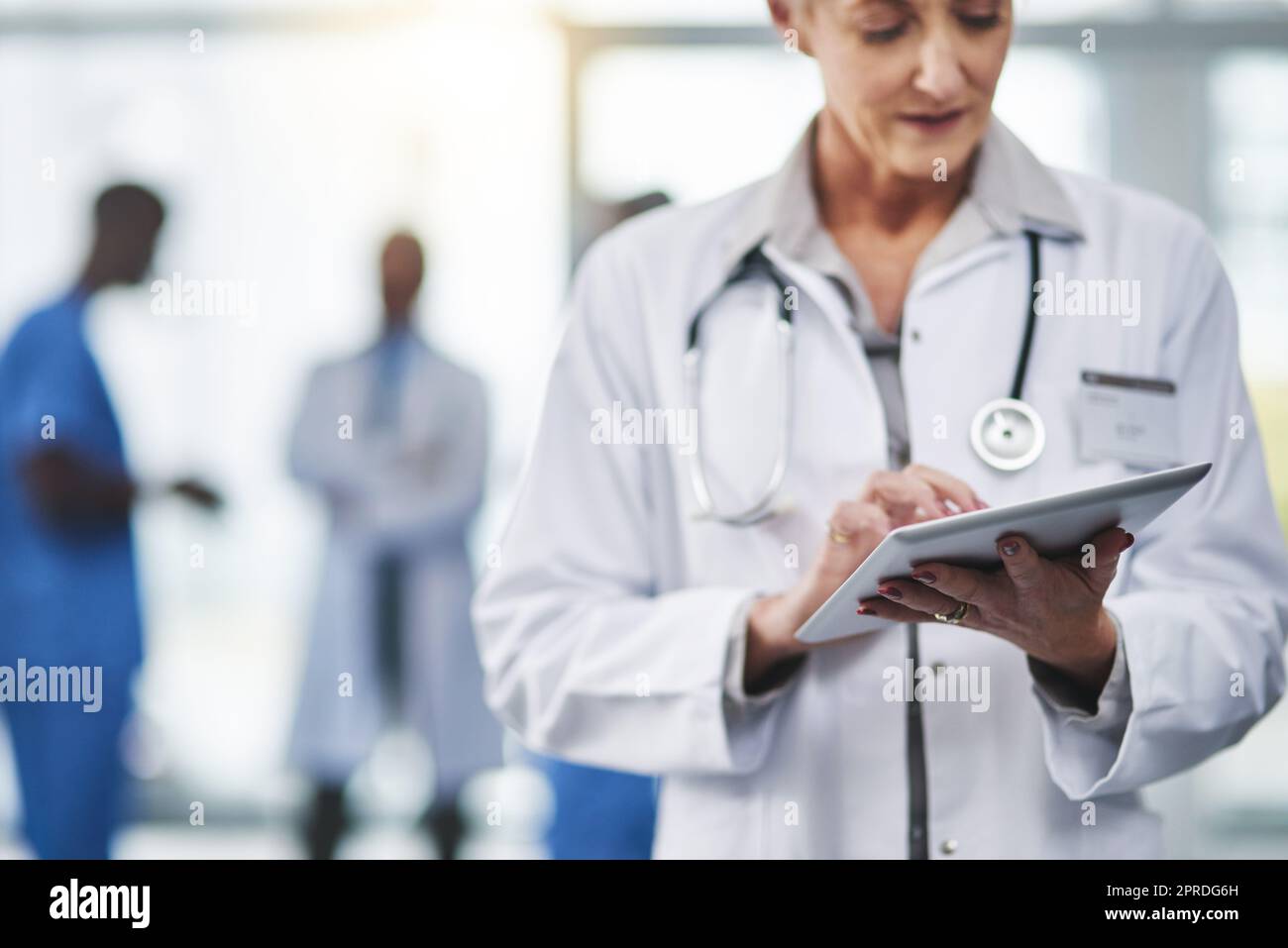 Mature female doctor on a digital tablet at the hospital. Smart elderly ...
