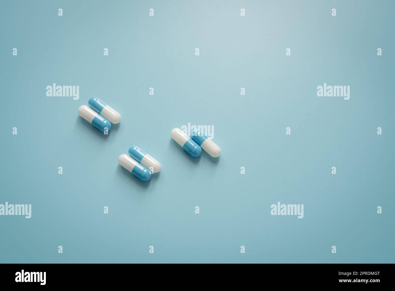 Pairs of white-blue antibiotic capsule pills on blue background ...