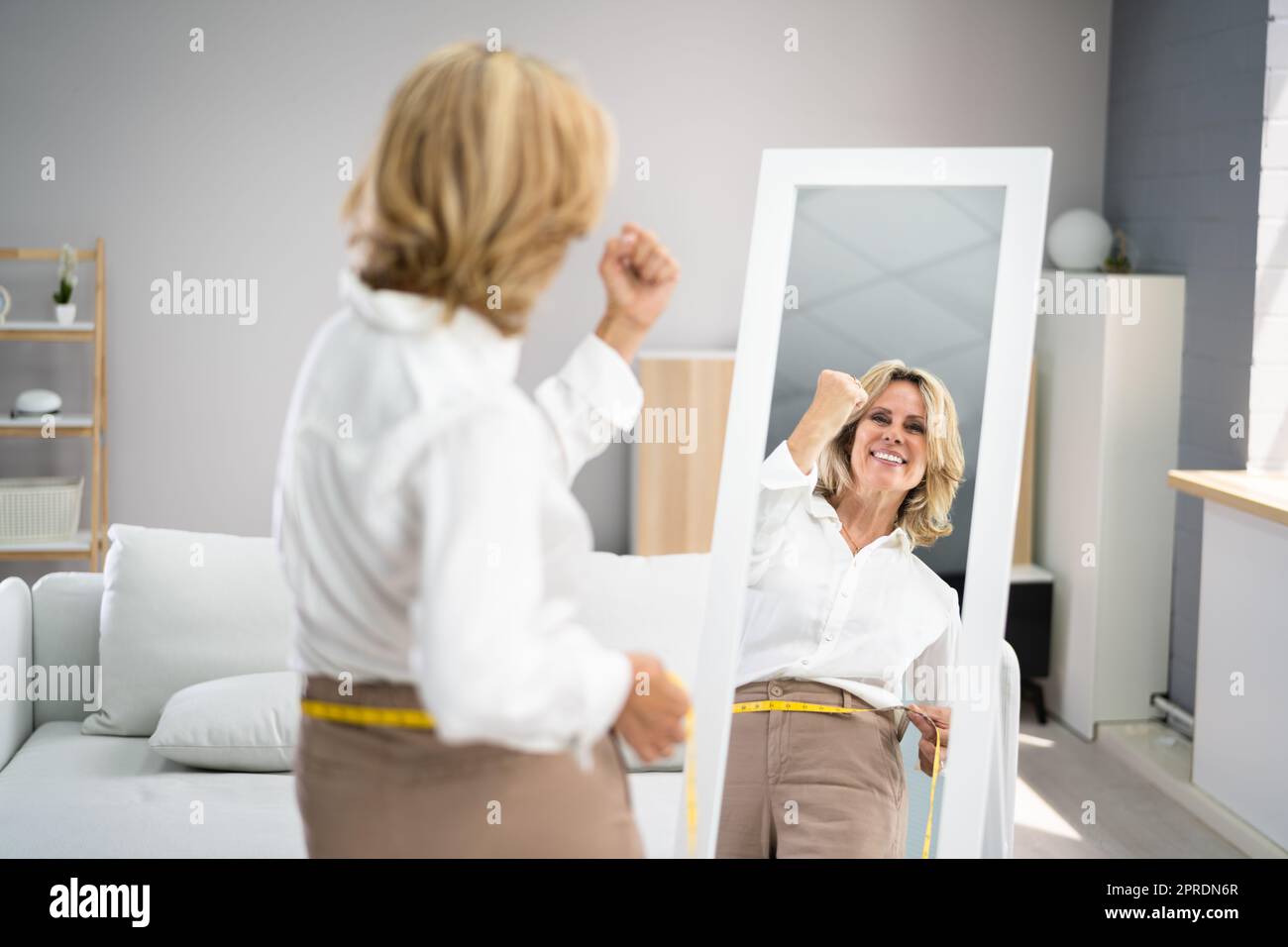 Smiling Slim Woman Looking At Her Reflection Stock Photo - Alamy