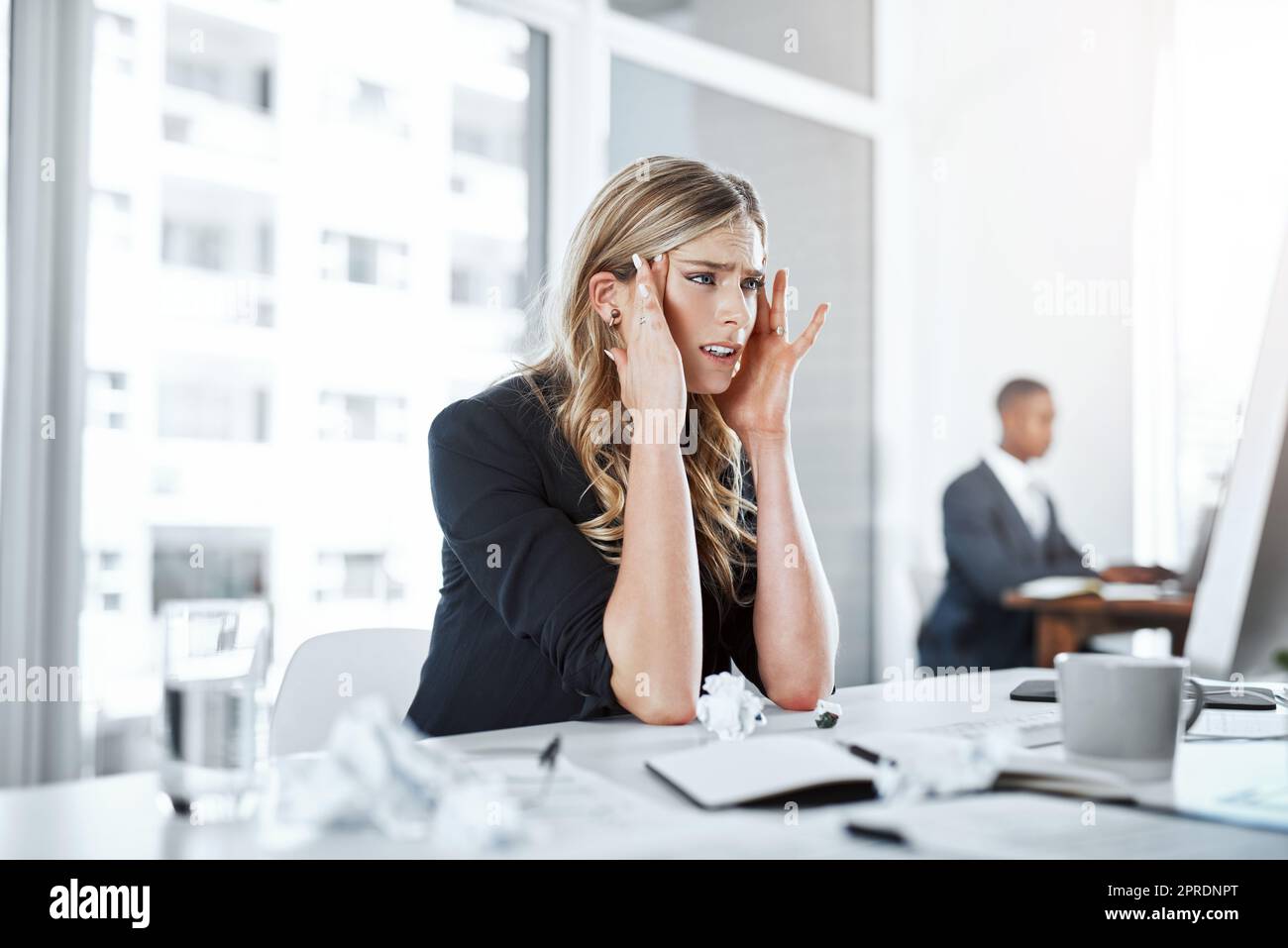 Taking work stress to the head. a young businesswoman experiencing stress while working at her ...
