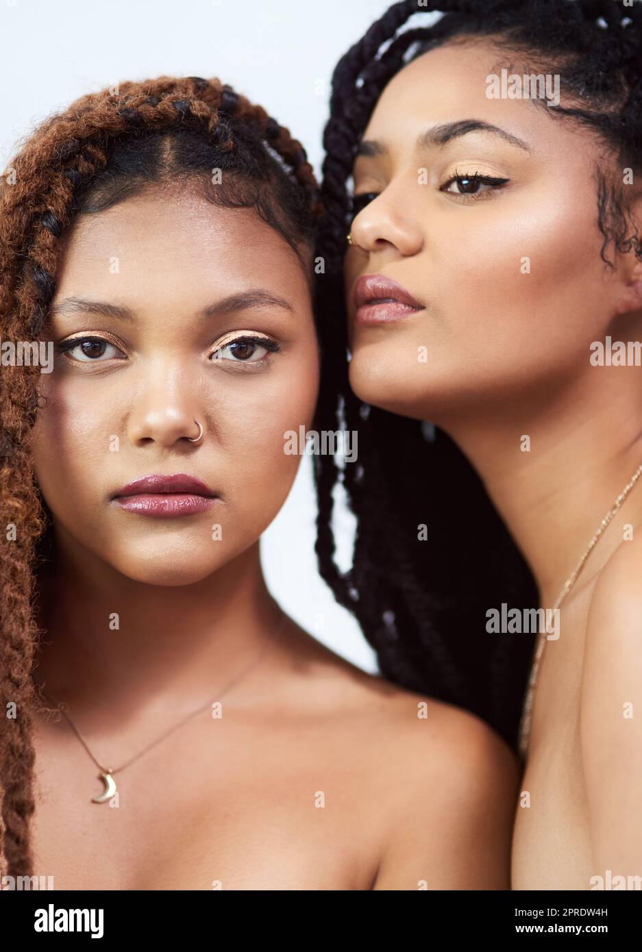 Together they glow. Studio shot of two beautiful young women posing against a grey background ...