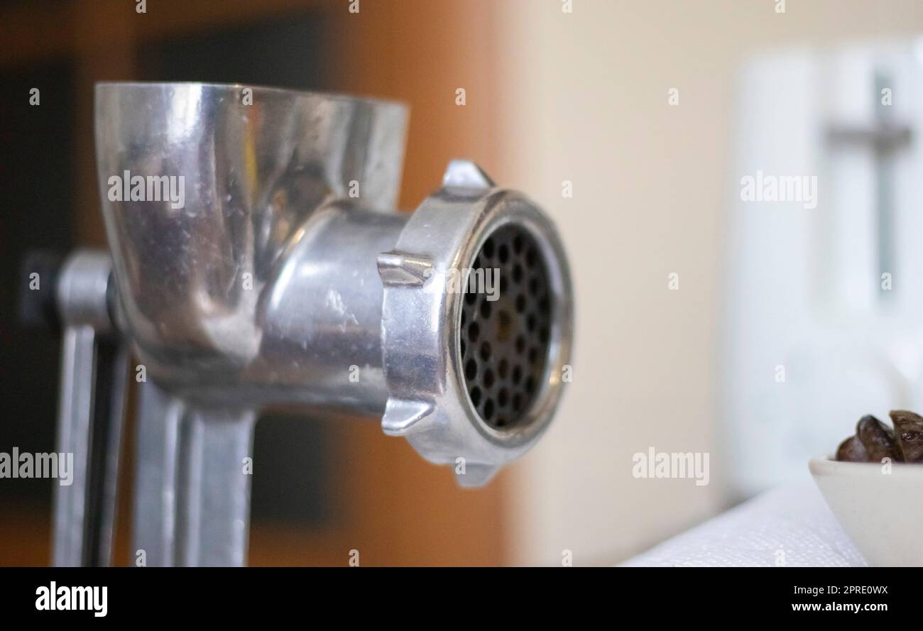 The classic manual iron meat grinder is fixed on the table. Antique ...