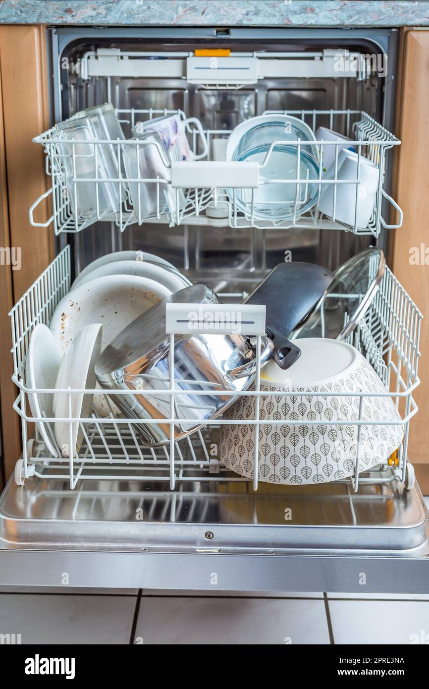 Open modern dishwasher with messy dishes in the kitchen, built-in ...