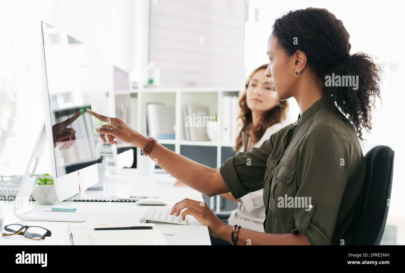 Teamwork is an asset to any company. two young businesswomen using a ...