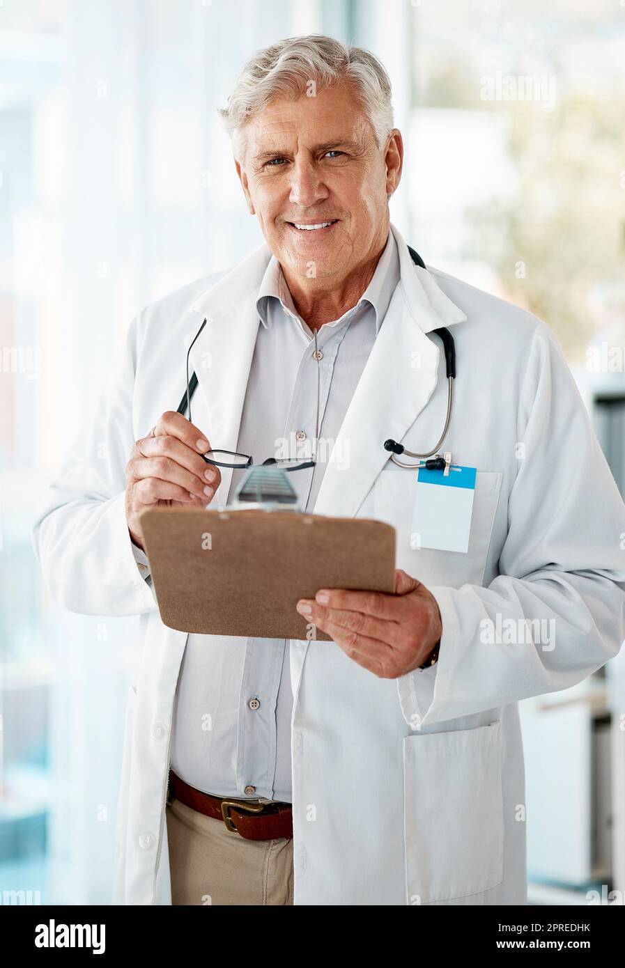 Confident mature male doctor reading patient records on clipboard in ...