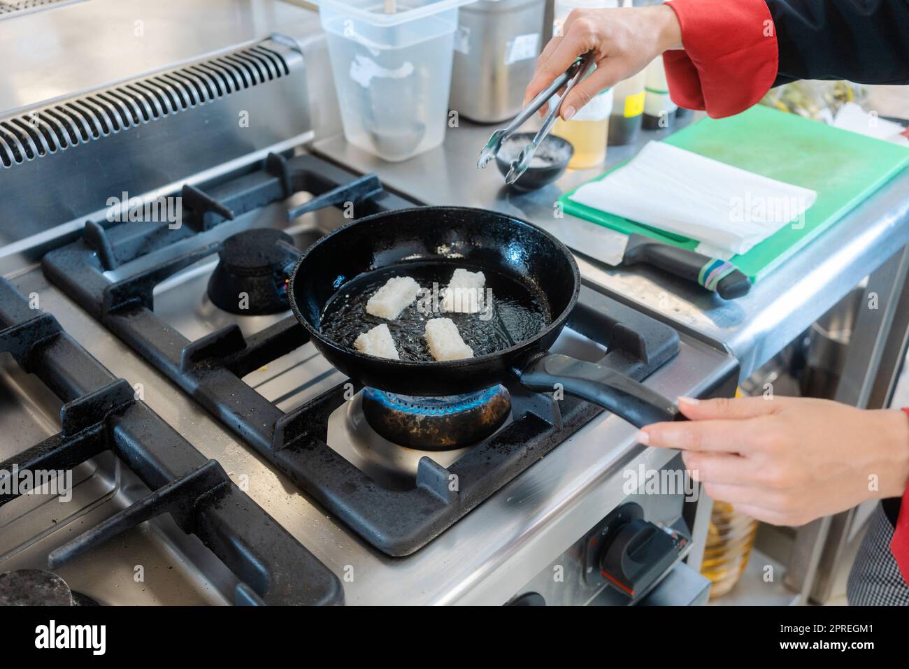A female chef pan-frying lard pieces in restaurant kitchen Stock Photo ...