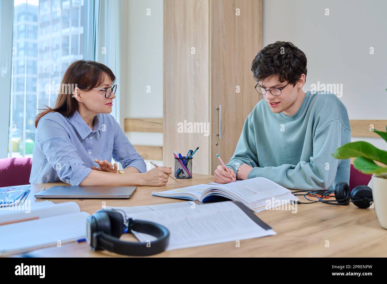 Female tutor teaching college student guy, in classroom at desk Stock ...